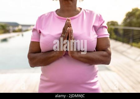 Midsection of african american woman meditating wearing sports clothes ...
