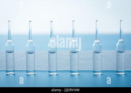 Ampules standing in a row on blue background Stock Photo - Alamy