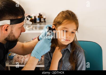 ENT doctor otolaryngologist looks through otoscope the ears of a little ...