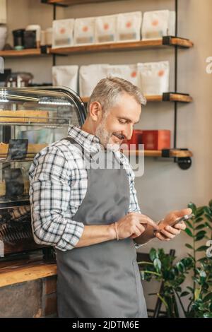 Man with smartphone standing sideways to camera Stock Photo - Alamy