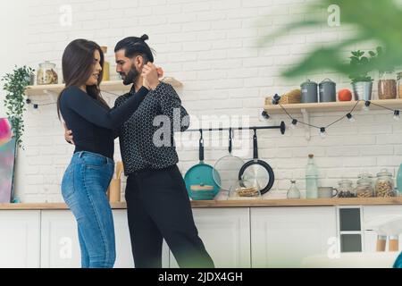 Attractive passionate couple in kitchen. Woman is sitting on kitchen ...