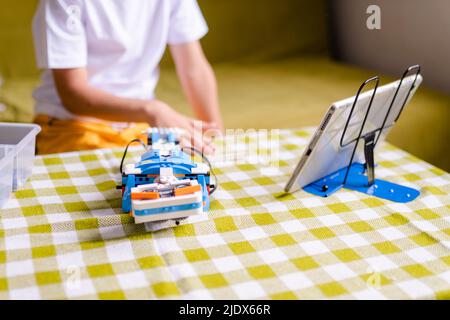Kid collects robot from plastics details and programmed on tablet ...