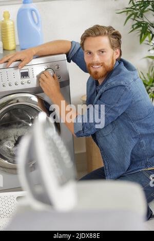 Man Doing Laundry Reaching Inside Washing Machine Stock Photo - Alamy