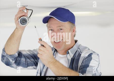 senior contractor installing overhead cctv camera Stock Photo - Alamy