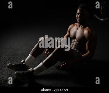 Afro american man doing abdominal exercises in a dark studio Stock ...
