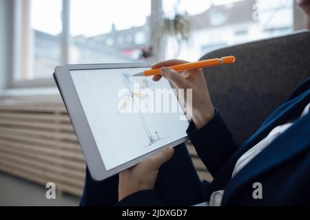 Hand of businesswoman drawing wind turbine on tablet PC with digitized ...
