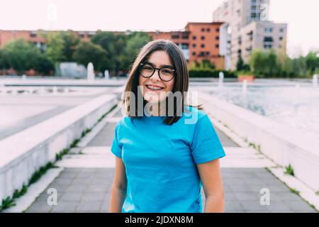 Happy girl wearing eyeglasses standing in front of friends on sunny day ...