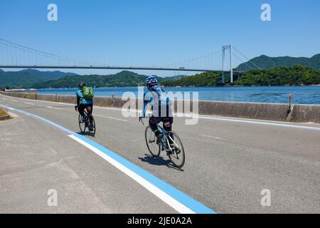 Cyclists riding along the Shimanami Kaido bike route between Onomichi ...