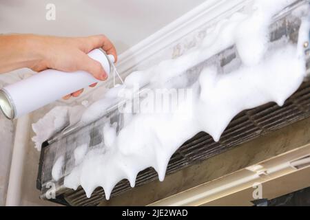 A man sprays special foam to clean air conditioners on the radiator ...