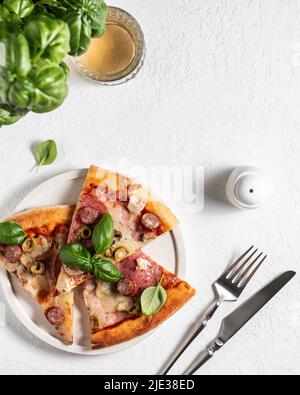 Three pieces of pizza in white plate, linen napkin and basil leaves on ...