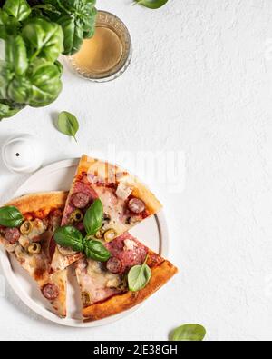 Three pieces of pizza in white plate, linen napkin and basil leaves on ...