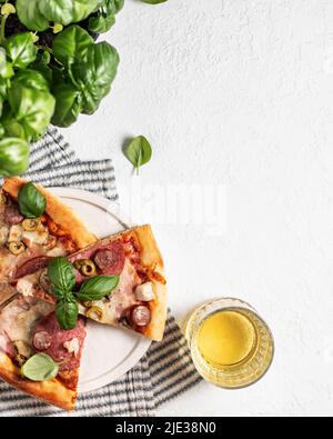 Three pieces of pizza in white plate, linen napkin and basil leaves on ...