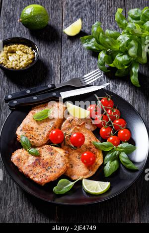 tomato basil pesto pork cutlets with fresh tomatoes, lime wedges and ...