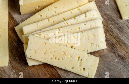 sliced natural cow's milk cheese, fresh yellow milk cheese on a board ...