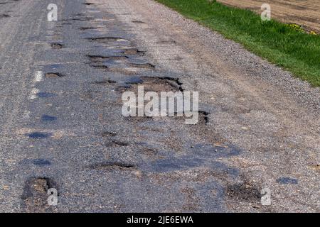 poor paved road with a lot of holes and potholes, poor transport ...