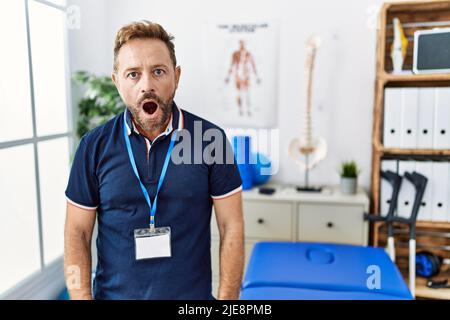 Middle age physiotherapist man working at pain recovery clinic smiling ...