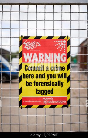 Forensic tagging warning sign on security fence - commit a crime here ...
