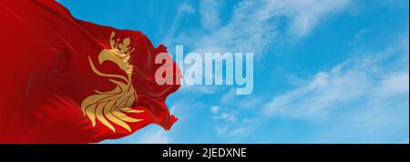 official flag of Skane , Sweden at cloudy sky background on sunset ...