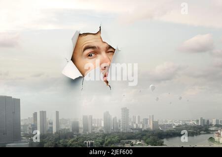 Male face through the hole in paper Stock Photo - Alamy