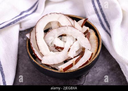 Dried coconut slices. Sliced dry coconut on dark background. Sun-dried ...