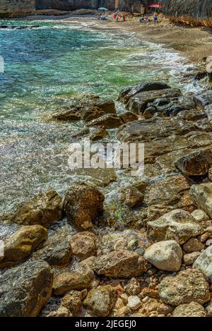 The stony coast of the Chianca Masitto beach. A small jetty with a boat ...