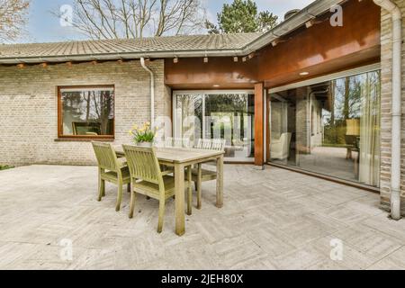 Neat paved patio with sitting area and small garden near wooden fence ...