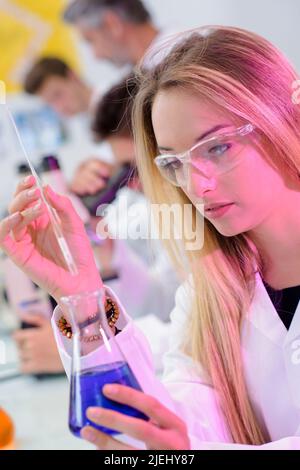 adult scientist and girl in goggles mixing reagents in tubes in ...