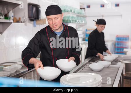 Kitchen worker arranging cleaned dishes Stock Photo - Alamy