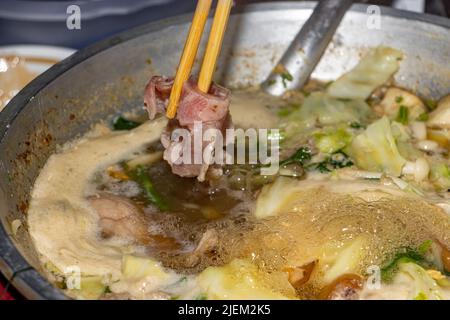 Preparing traditional Suki soup by cooking in a pot Stock Photo - Alamy