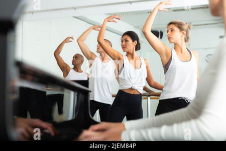Four dancers doing exercises on stretching ballet barre Stock Photo - Alamy