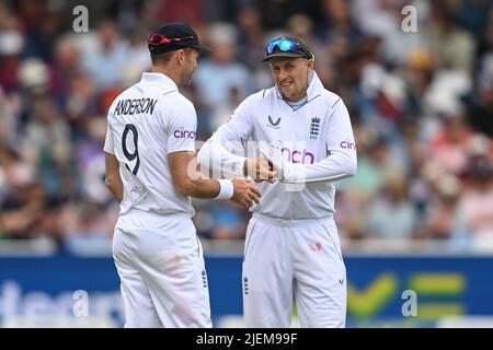 Joe Root of England (R) polishes the ball fro James Anderson of England ...