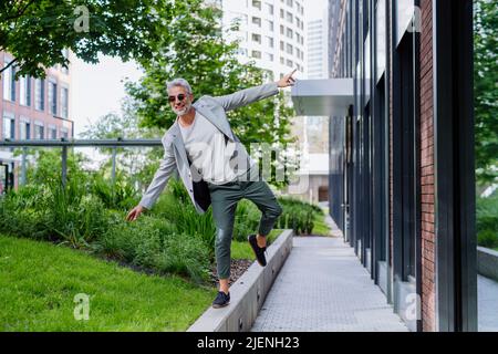 Portrait of happy energetic mature businessman with arms outstretched ...
