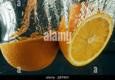 Oranges halves falling in water with splash on blue background Stock ...