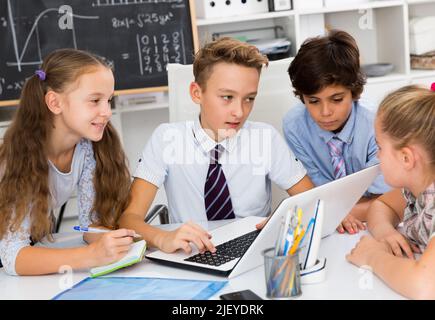 Group of children near laptop talking about mathematics indoors Stock ...