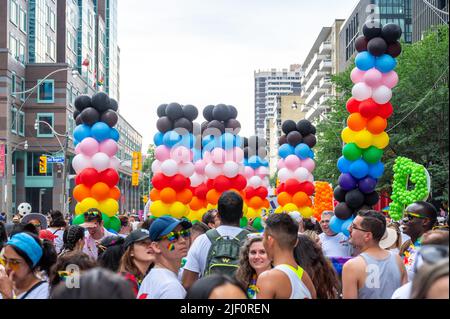 Crowd of people marching in Bloor Street during Pride Parade. They are holding columns of balloons with rainbow colors Stock Photo Alamy
