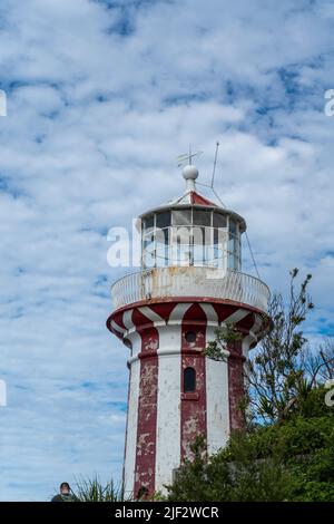 A vertical shot of a white lighthouse with a red top part against the ...