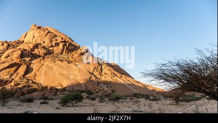 Bold rock formations glowing bright orange in the last rays of the ...