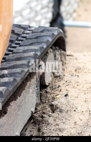 A vertical shot of an excavator track rubber tires during construction ...