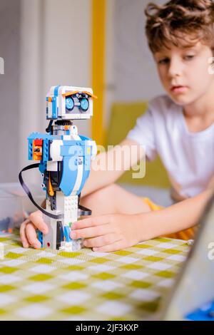 Kid programming robot from plastics details and programmed on tablet ...