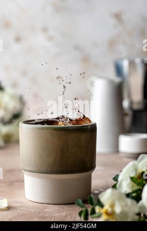 Splashing of coffee in ceramic glass on the table in composition with ...