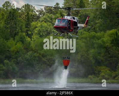 A 413th Flight Test Squadron UH-1 Huey fills a water bucket from ...