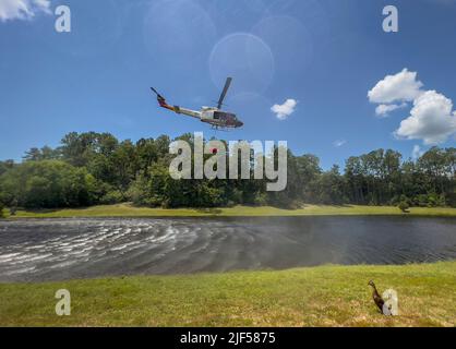 A 413th Flight Test Squadron UH-1 Huey fills a water bucket from ...