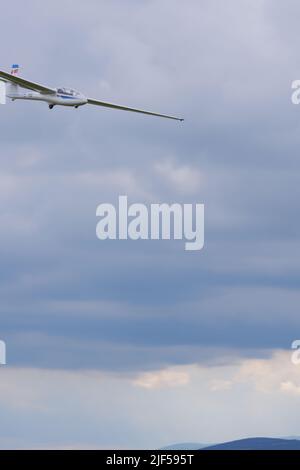 Glider with no engine flies within dark clouds over hills Stock Photo ...