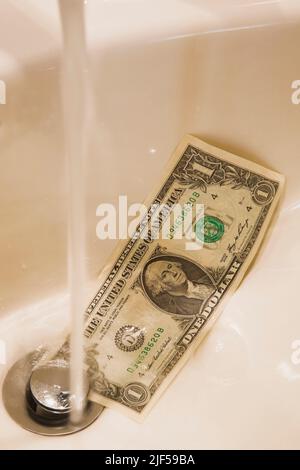 US Dollar going down the drain in stainless steel kitchen sink Stock ...