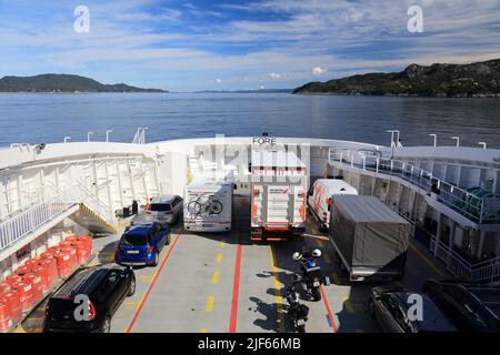 A ferry carries passenger cars as it crosses the Mekong river outside ...