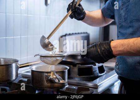 Chef separating water from rice using strainer in commercial kitchen ...