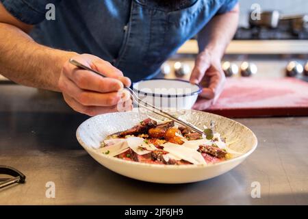 Closeup of chef garnishing herb on main dish on counter in commercial ...
