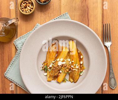Top view of braised endives with orange juice on a wooden table next to ...