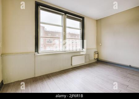 Plastic window and radiator on white wall in empty light room at home ...