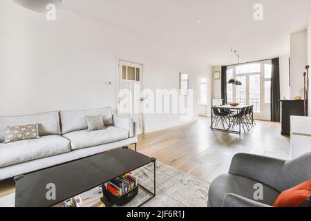 Shabby wooden table with chairs and vase located near comfortable couch ...